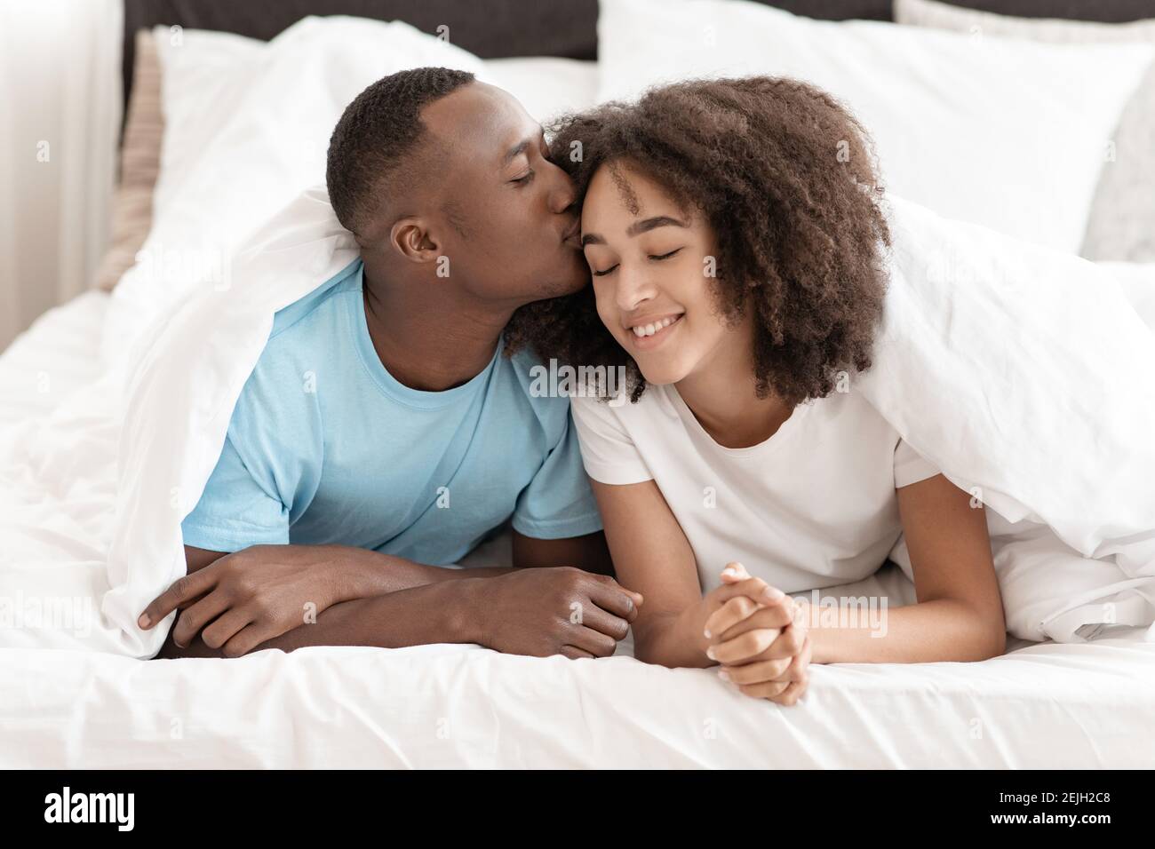 Happy young handsome african american husband kissing woman on forehead ...