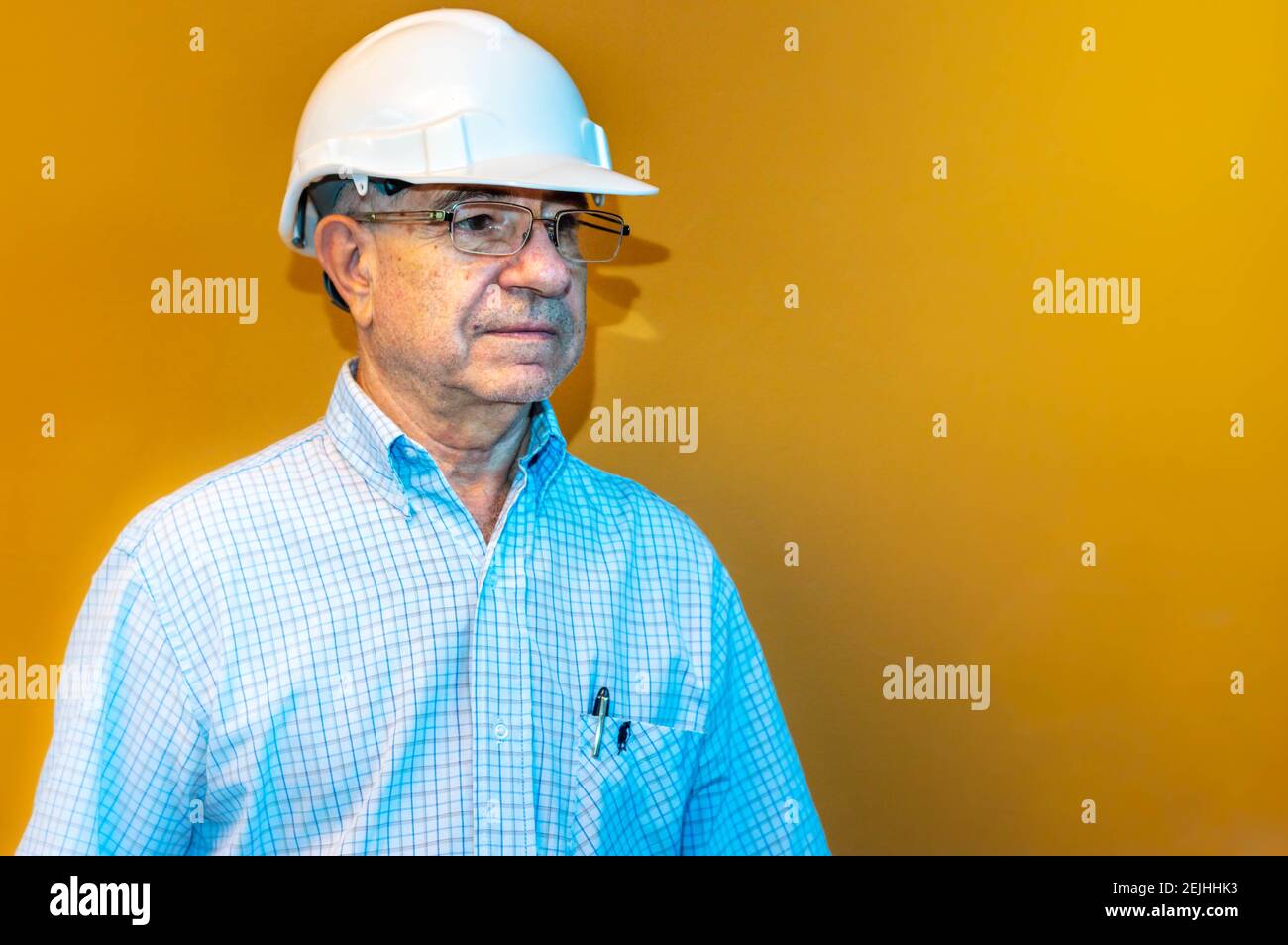 Civil engineer wearing a helmet and standing against a yellow ...
