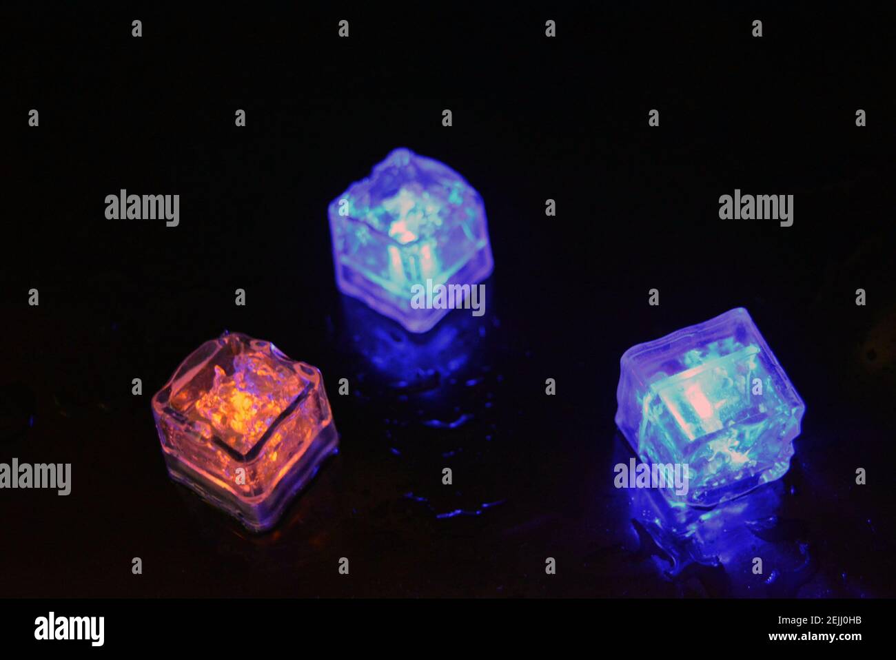 Beautiful plastic yelloe, blue glowing ice cubes on a glossy black ...