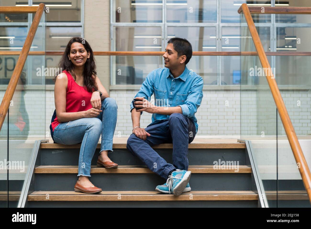 Two work colleagues chatting, listening and catching up in the communal ...