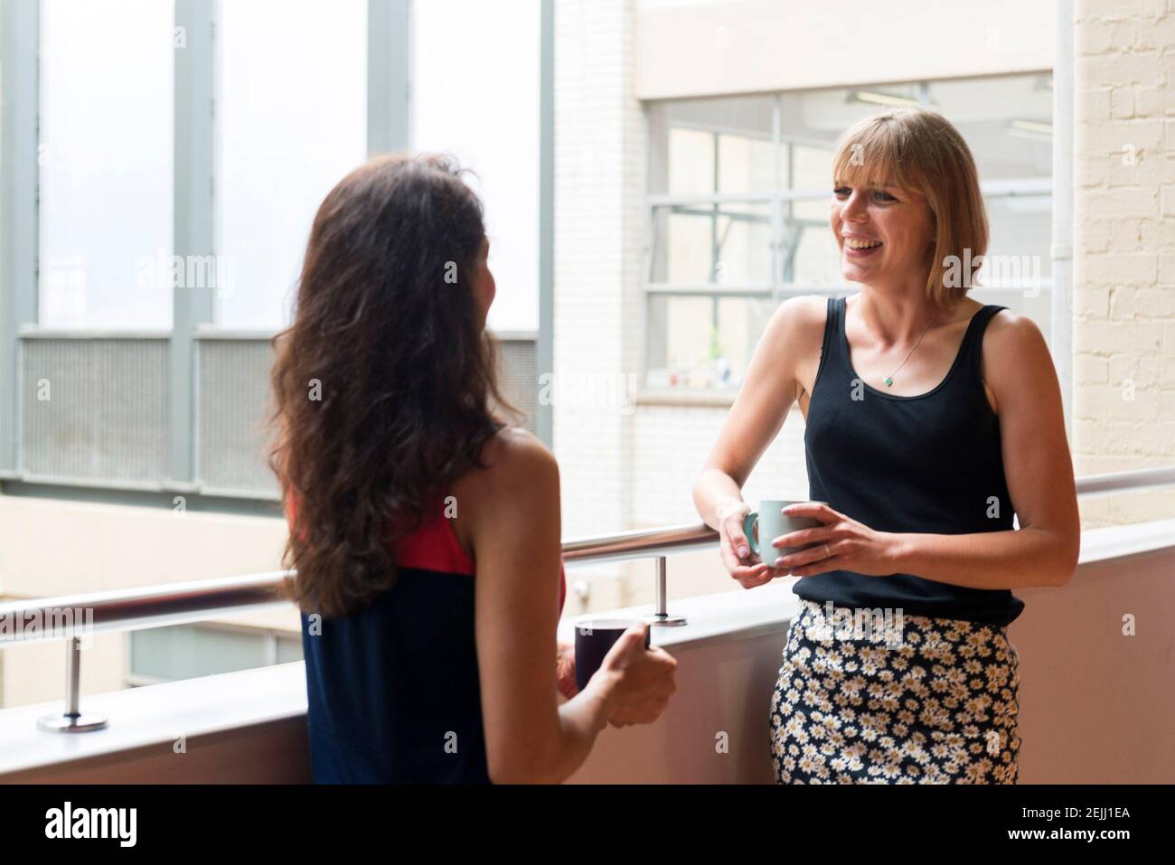 Two work colleagues chatting, listening and catching up in the communal ...