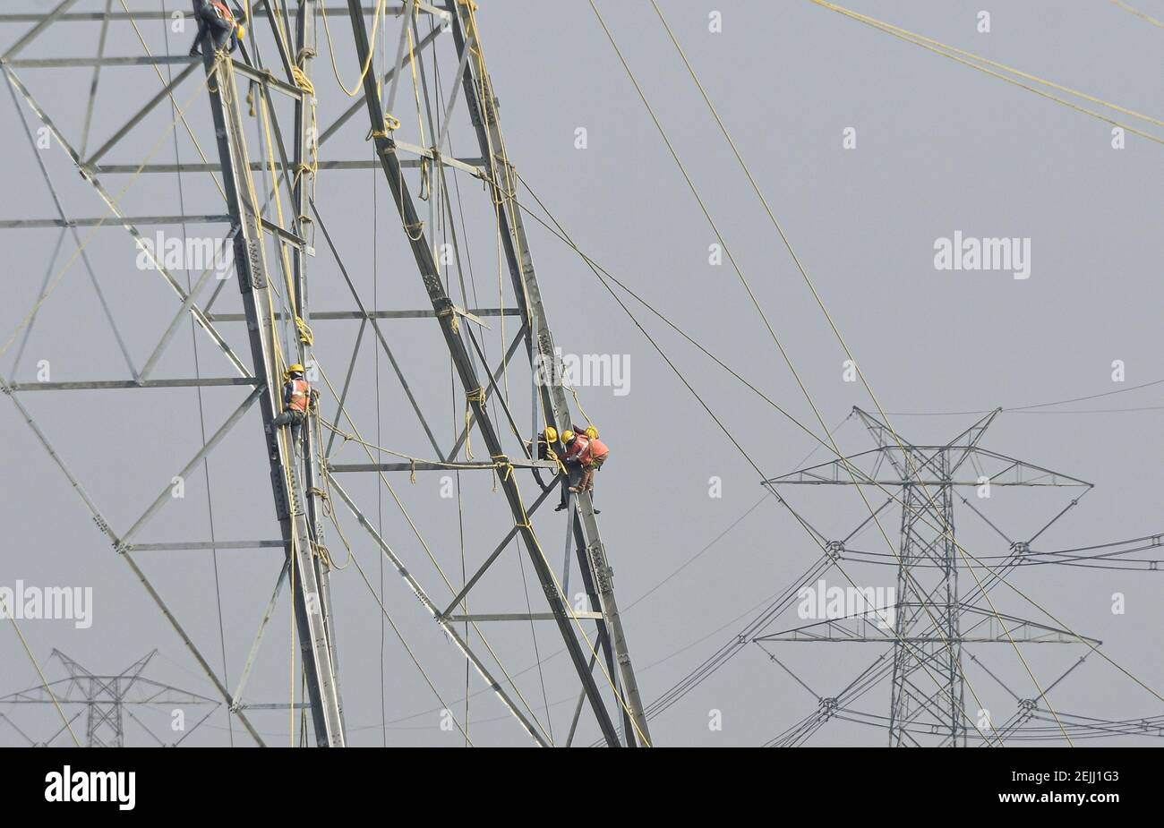 Electrical engineers climb on an overhead electricity pylon to work on ...