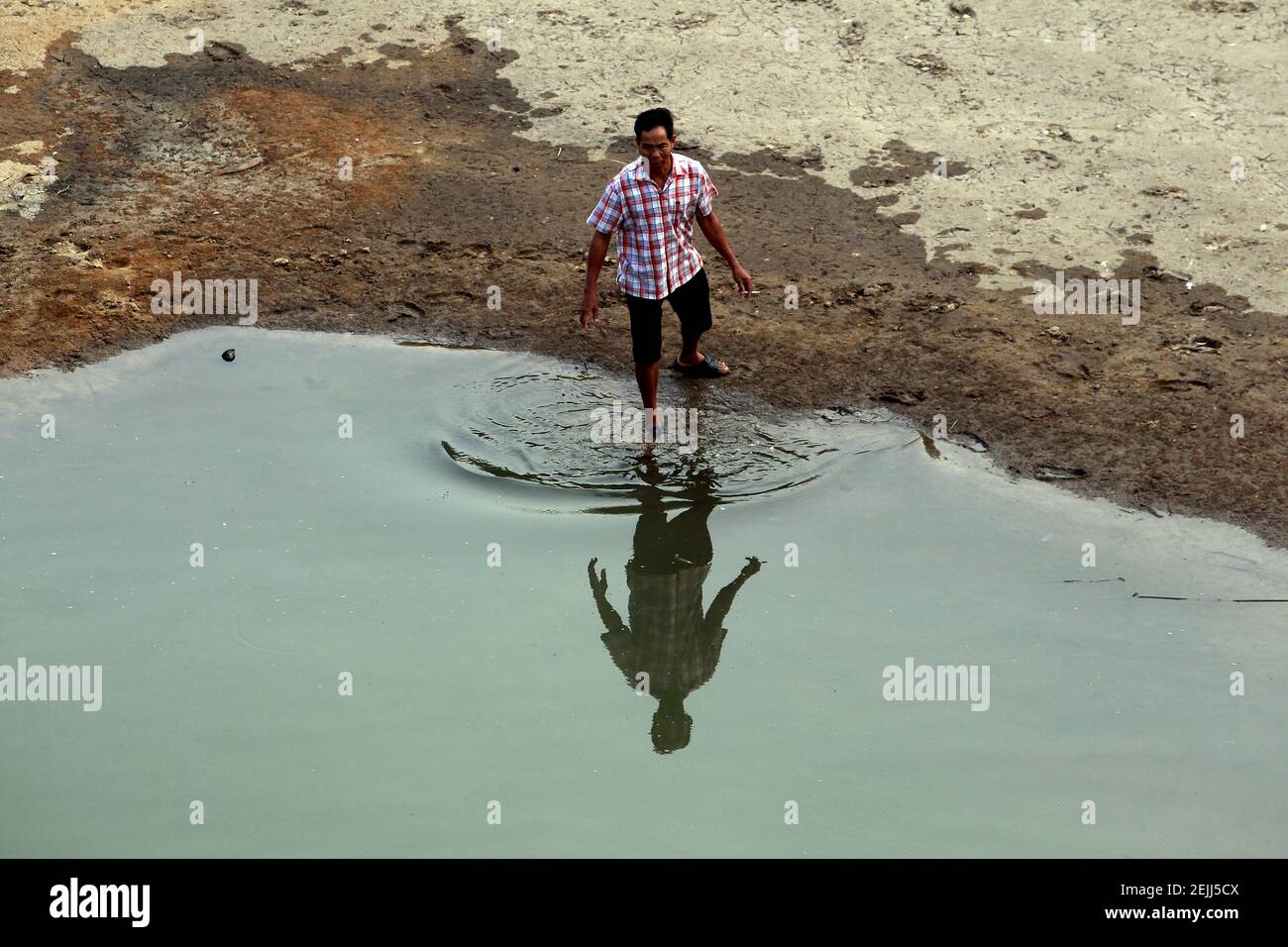 A villager walks in a dry Yom River during a drought season in Phichit ...
