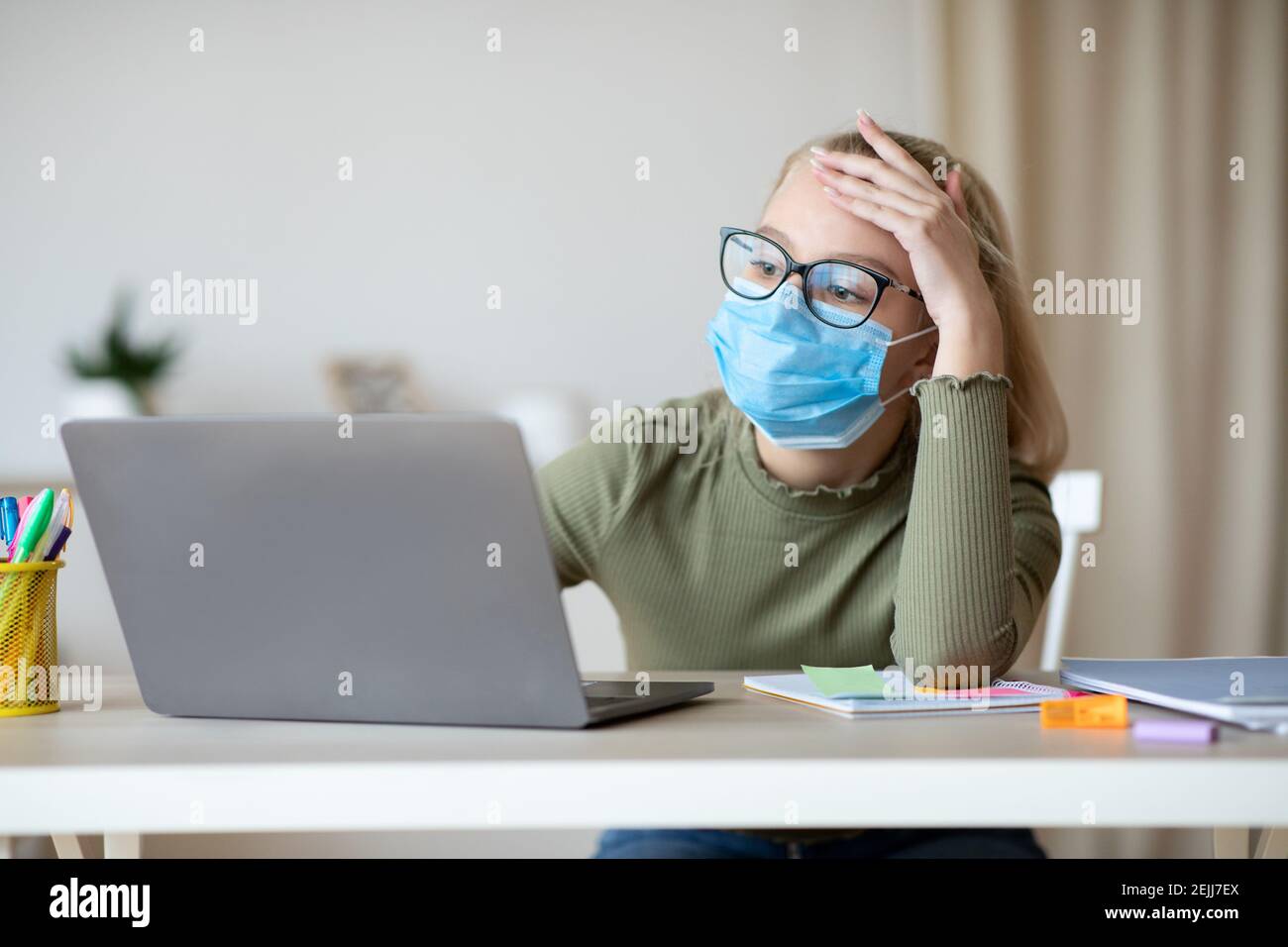 Bored school girl in face mask using laptop, studying online Stock ...