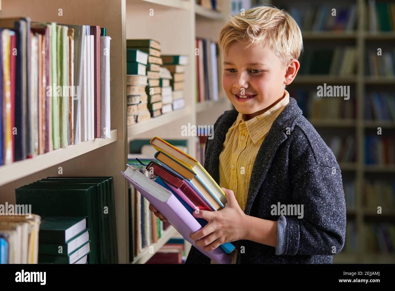 child boy holding books in hands in library, enjoy beind educated ...