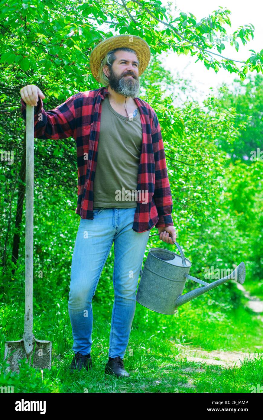 Farm. Smiling man with watering can and shovel. Farmer preparing to ...