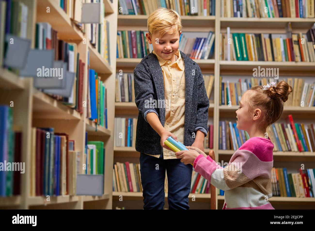boy and girl stand talking in library, discussing books, choose books ...