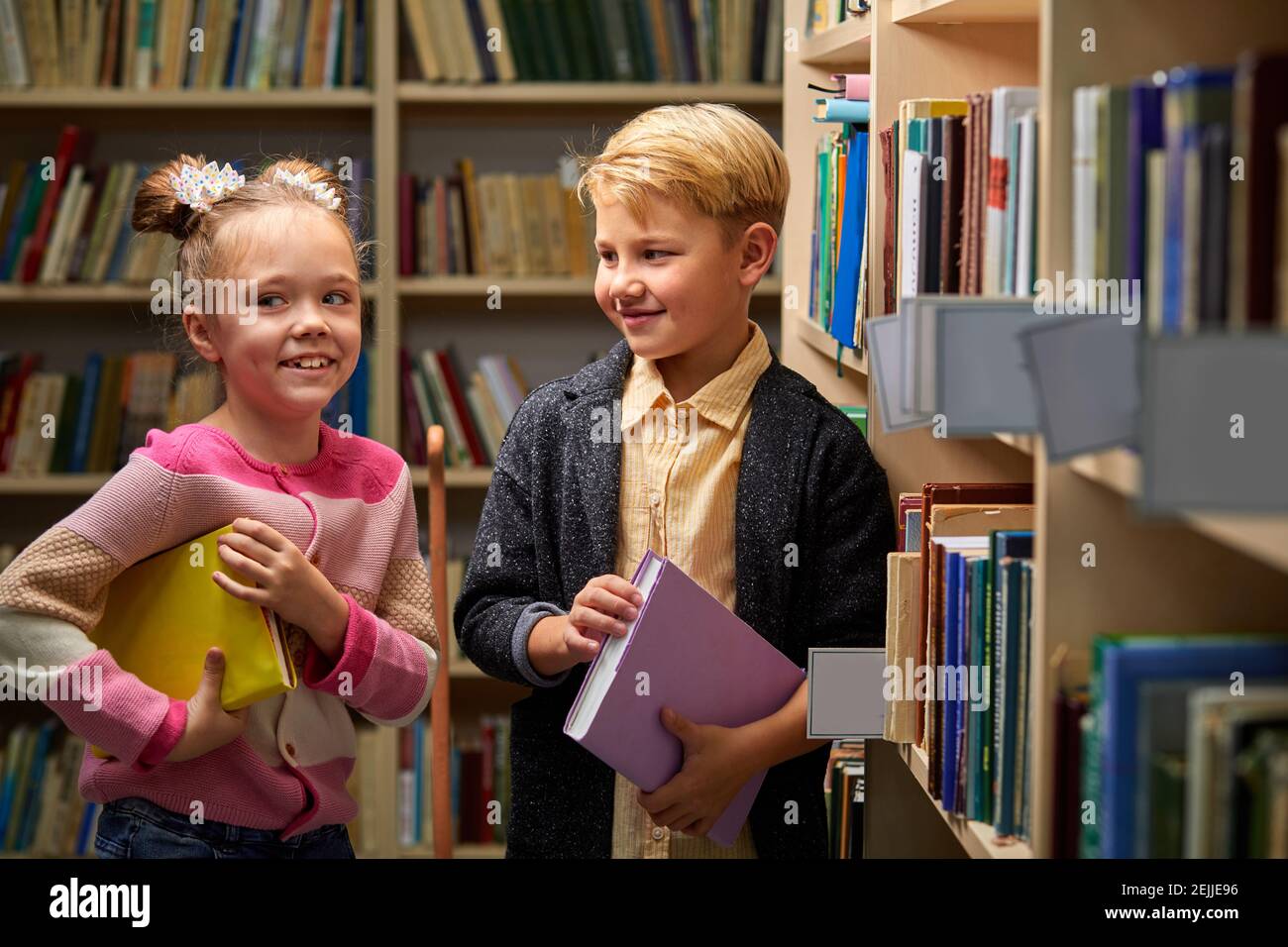 children have fun in the library, girl and boy talking and laughing ...