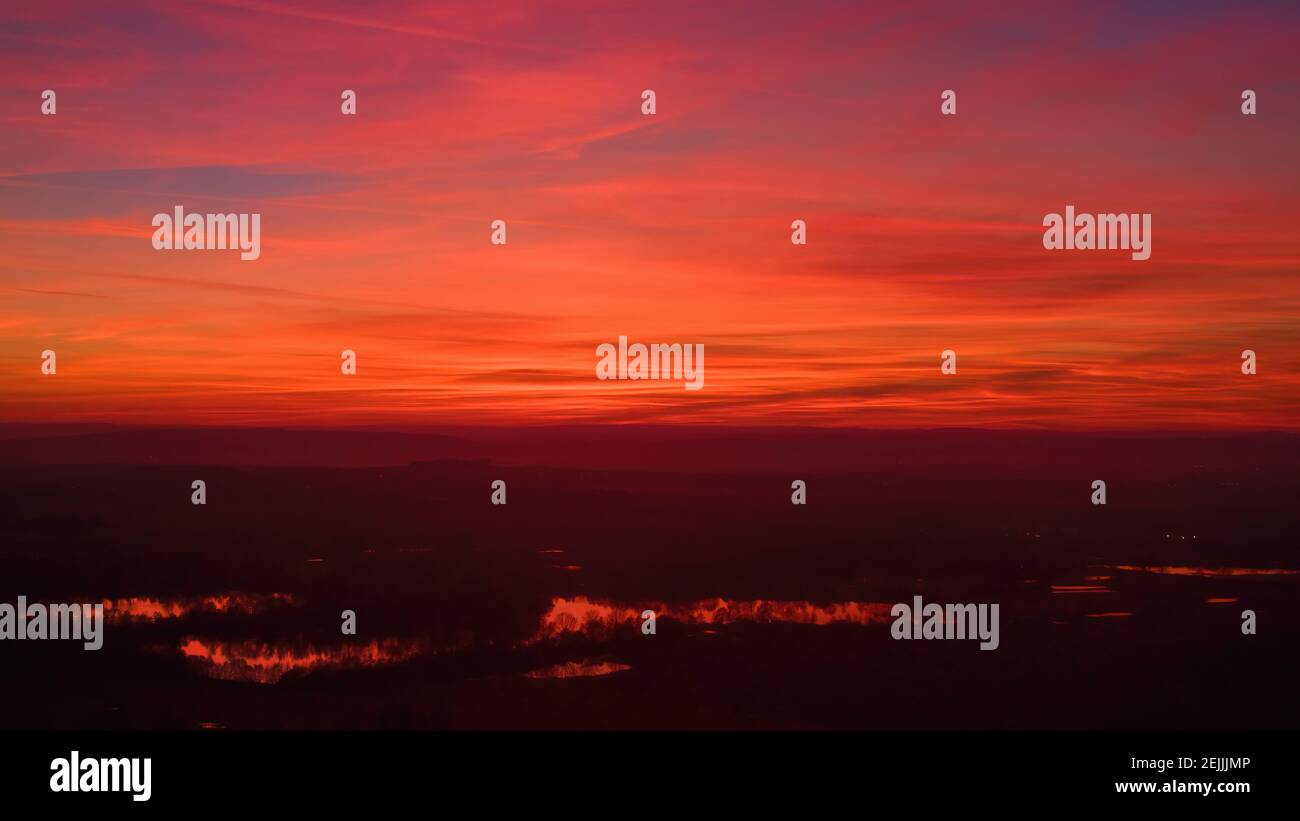 Red-orange sky after sunset. Red clouds are reflected in the lakes ...