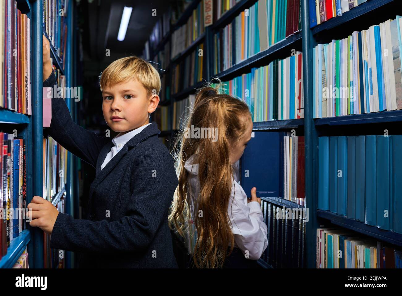 school children in library choosing books standing between shelves back ...