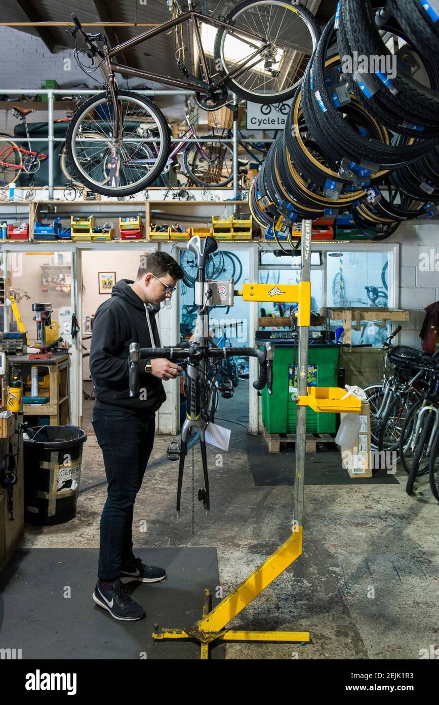 A bike mechanic works on fixing a bike in a cycle industry business ...