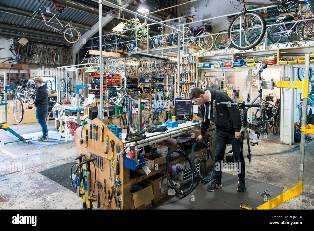 A bike mechanic works on fixing a bike in a cycle industry business ...