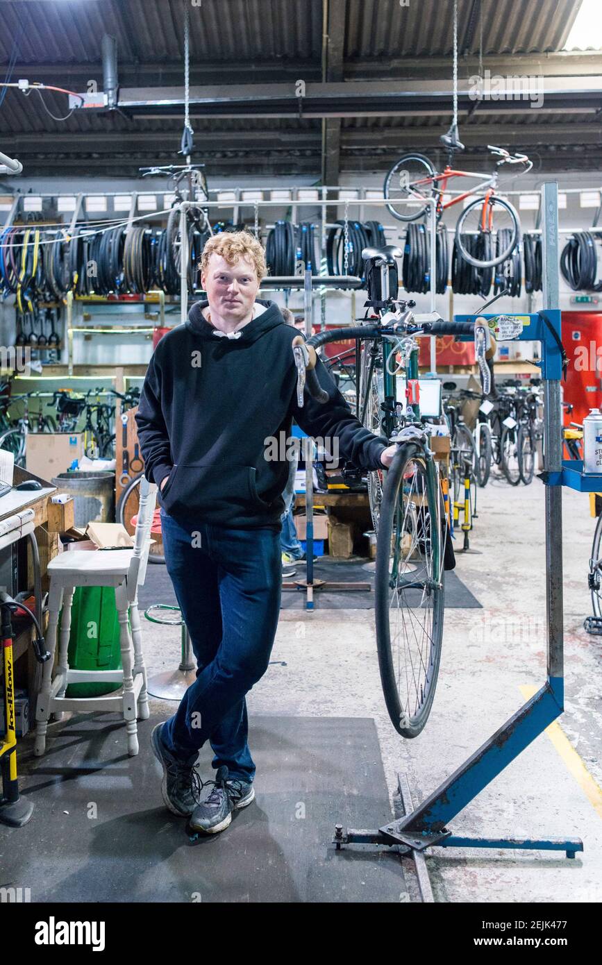 A bike technician stands at his work station and poses for a portrait ...