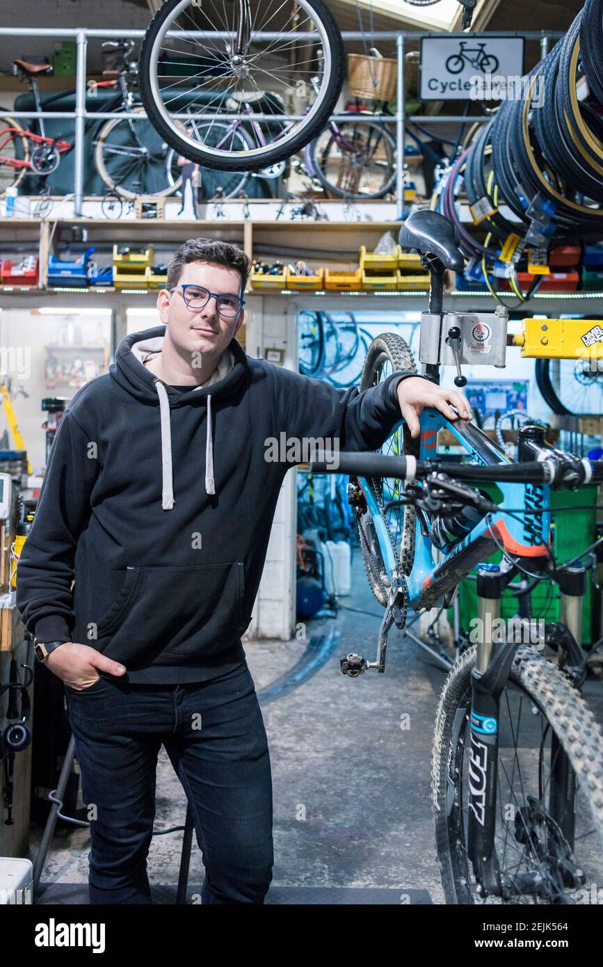 A bike technician stands at his work station and poses for a portrait ...