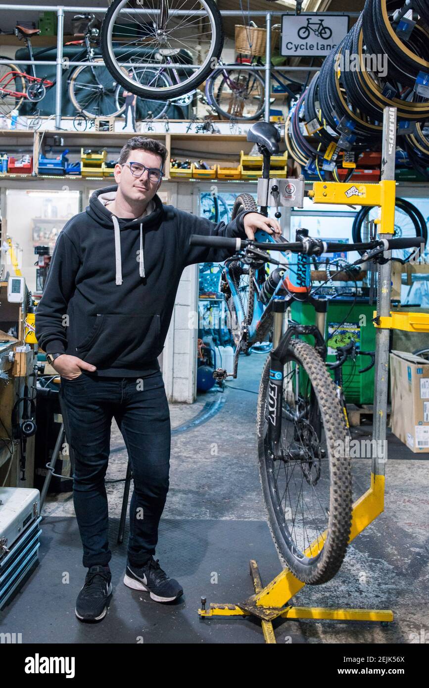 A bike technician stands at his work station and poses for a portrait ...