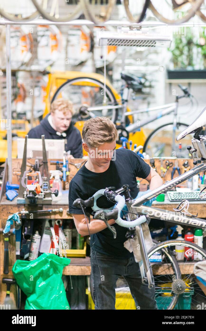 A bike mechanic works on fixing a bike in a cycle industry business ...