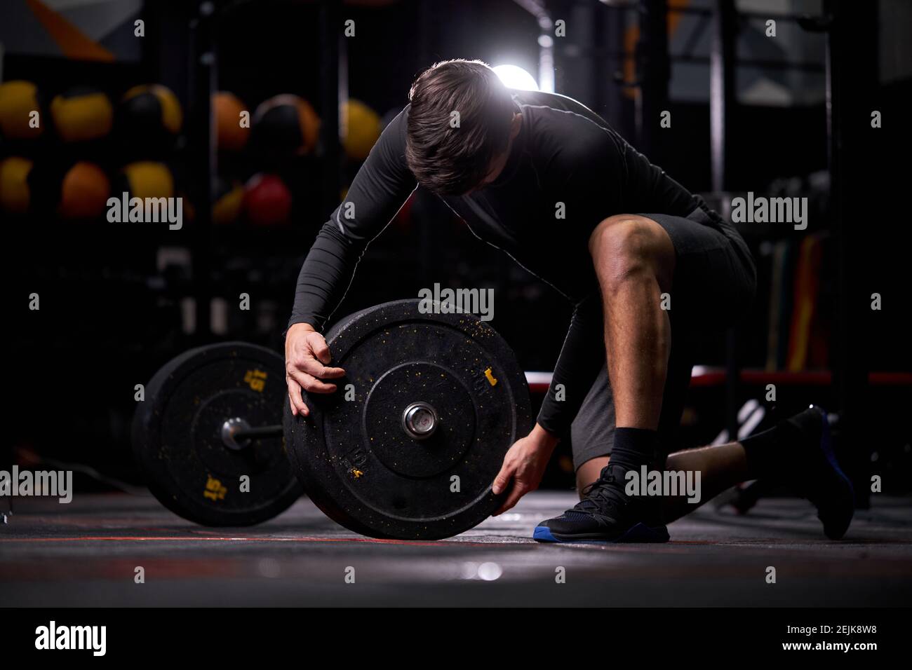 Athlete male adding weight plates on barbell, young caucasian fit guy ...
