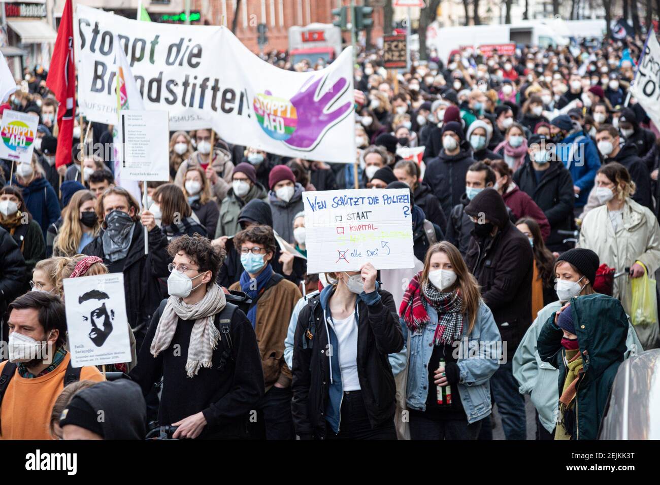 Protesters wearing masks march while holding portraits and placards ...