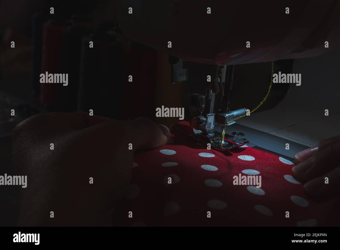 A sewing machine is shown up close only illuminated with its work light ...