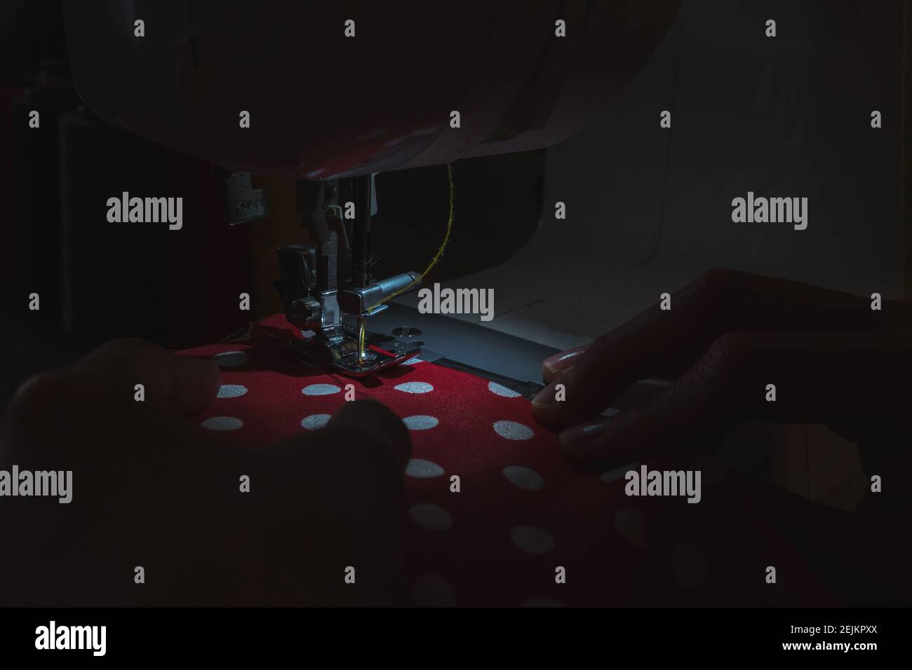 A sewing machine is shown up close only illuminated with its work light ...