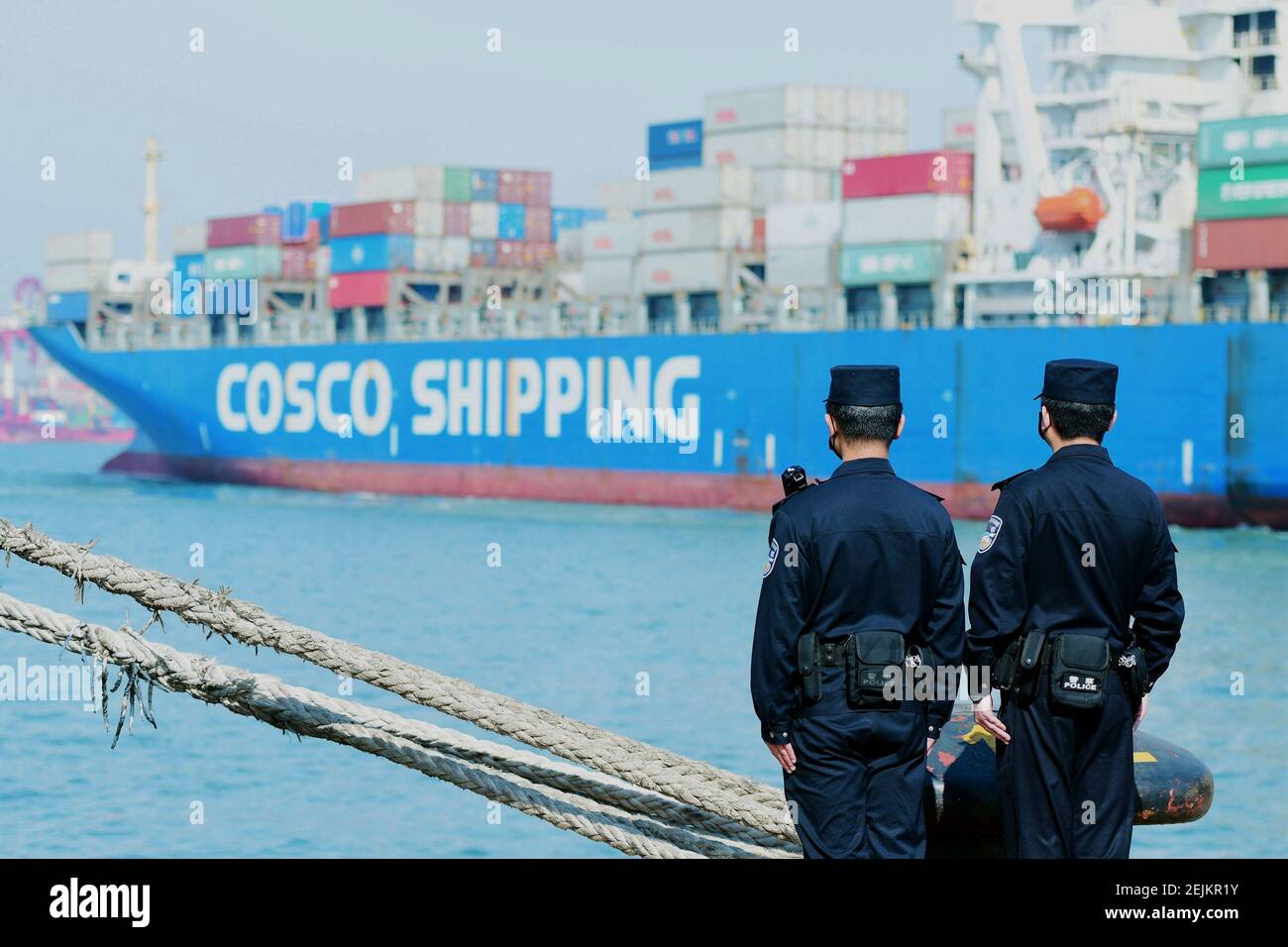 Chinese police officers watch a container ship of COSCO Shipping ...