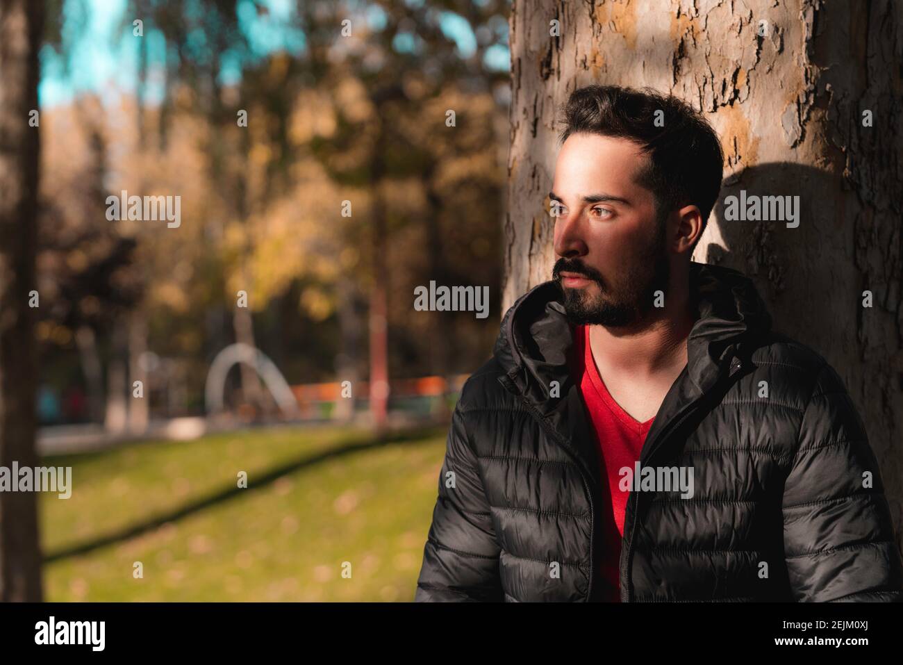 Shallow focus of a young man standing under a tree in the shadow Stock ...