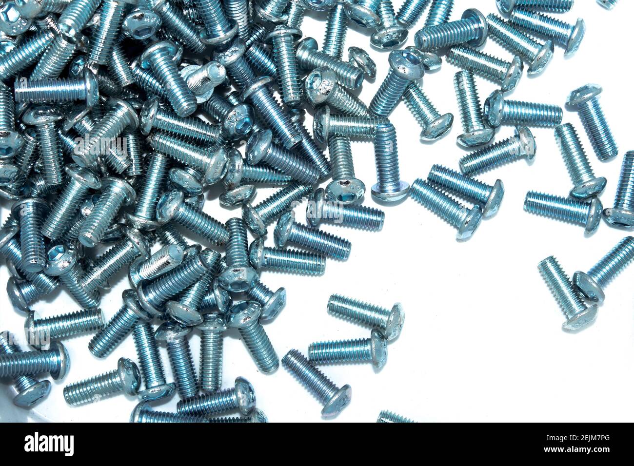 Lots of big industrial galvanized screws on a pile on white background ...
