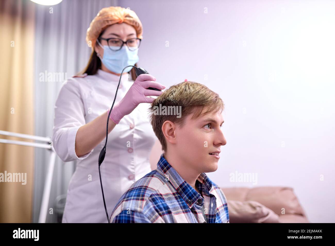 doctor dermatologist diagnoses structure of hair of man with a special ...