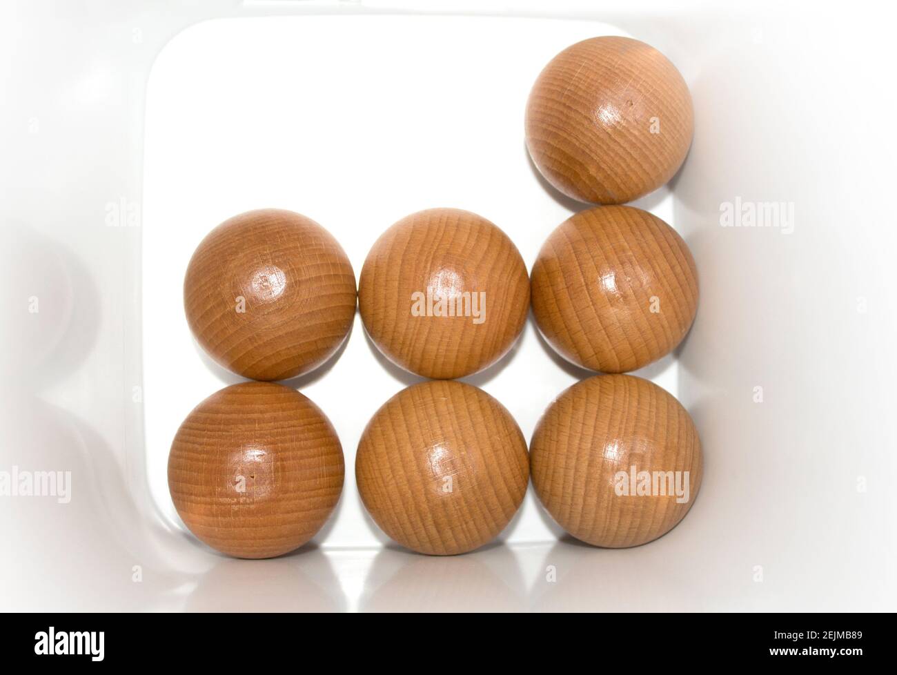 Seven round wooden balls in a white square box Stock Photo - Alamy