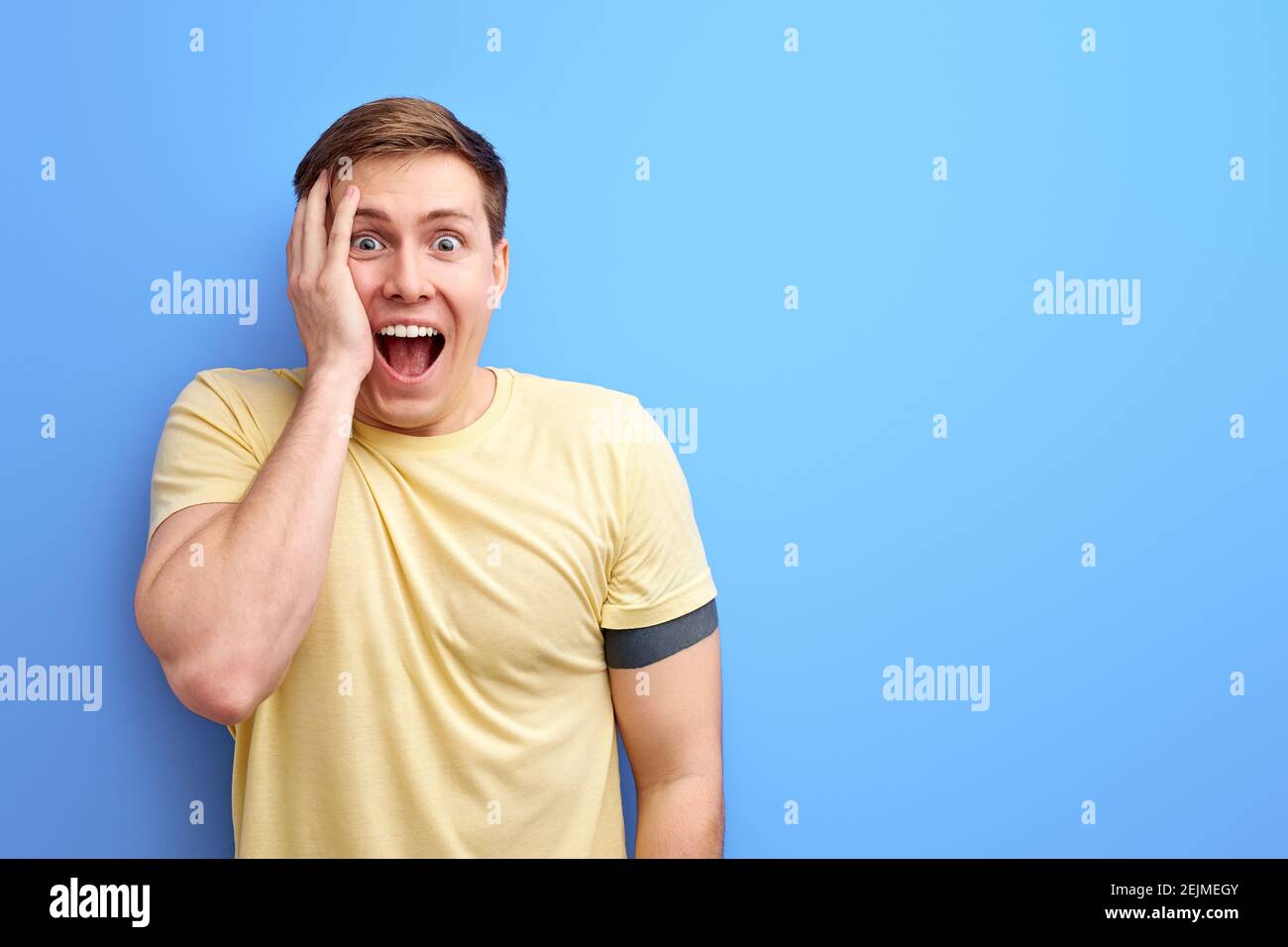 amazed man screaming in surprise or delight and closing face with hand ...