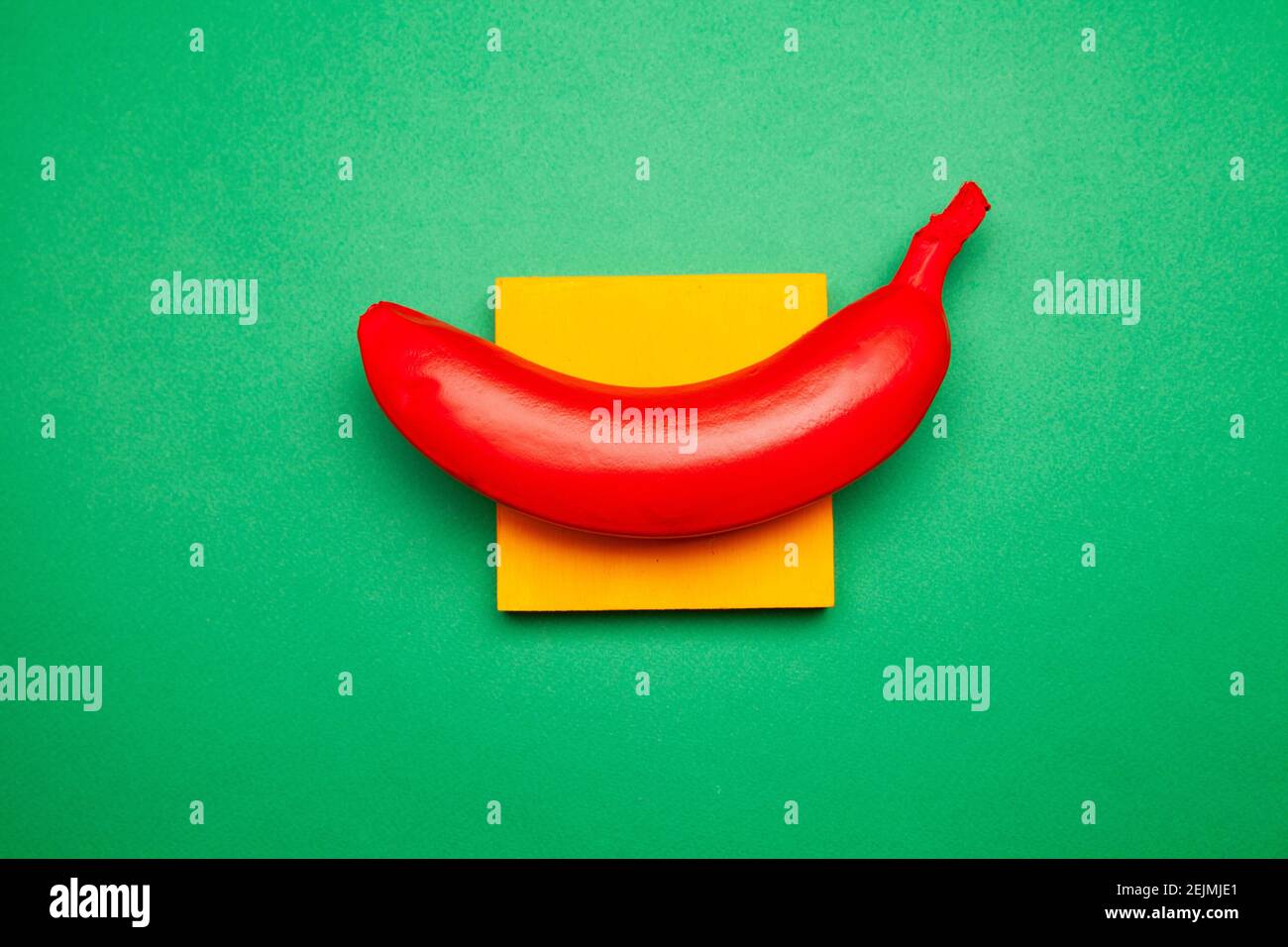 Bright composition of red banana and yellow sticky notes on green ...