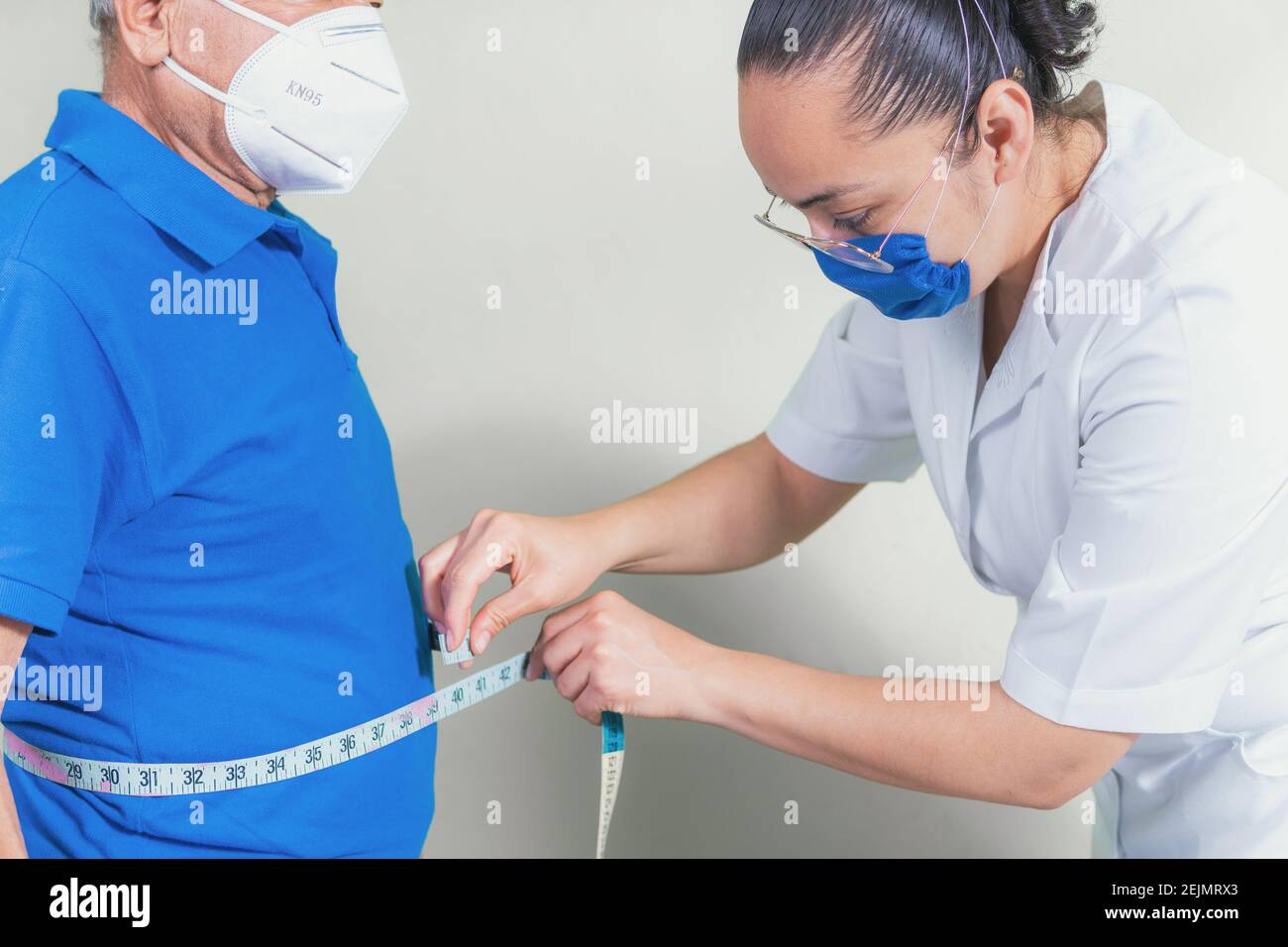 View of a nurse passing the tape measure on the height of an older man ...