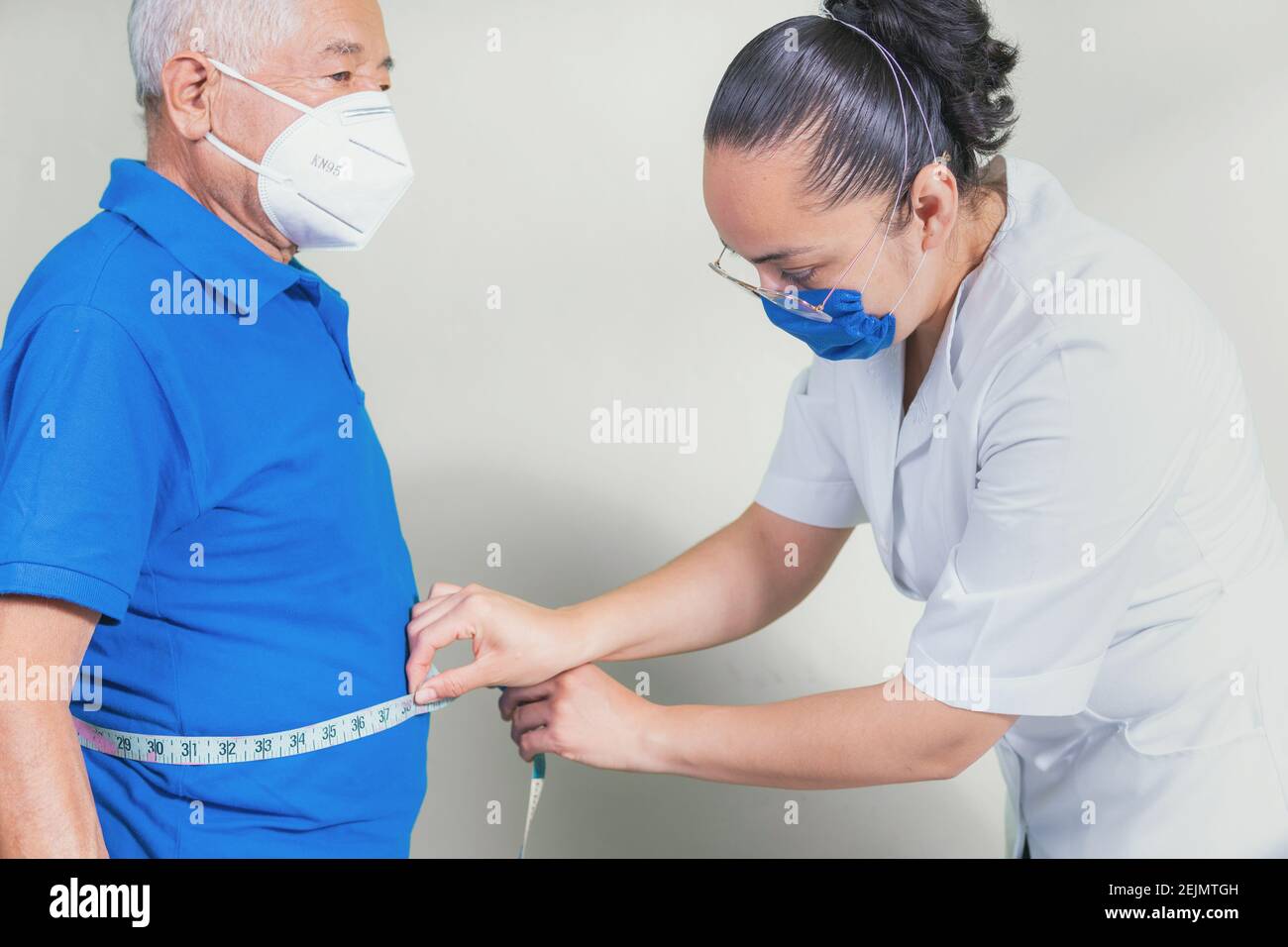 View of a nurse passing the tape measure on the height of an older man ...