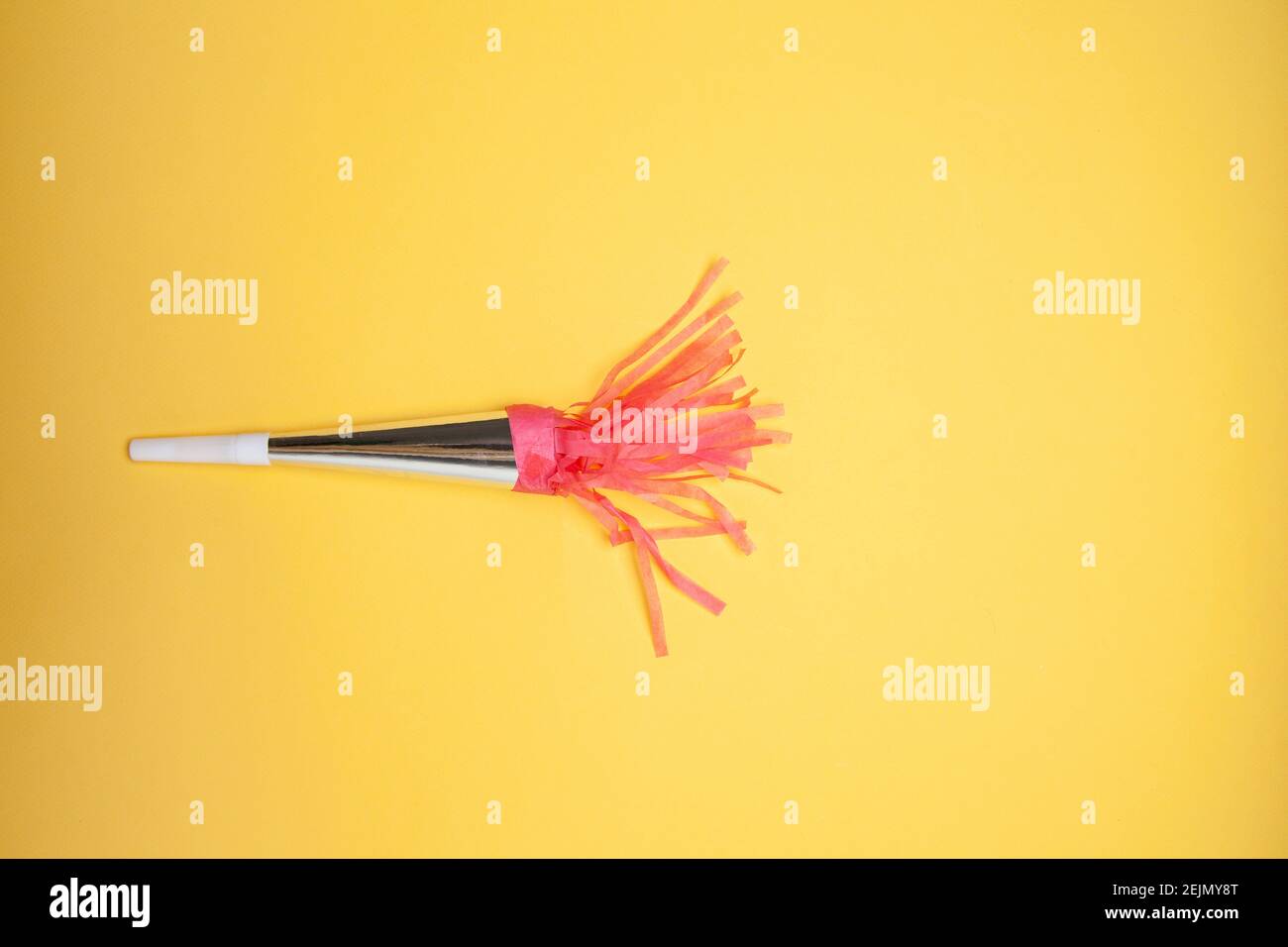 Party horn and scattered shiny confetti on orange background Stock ...