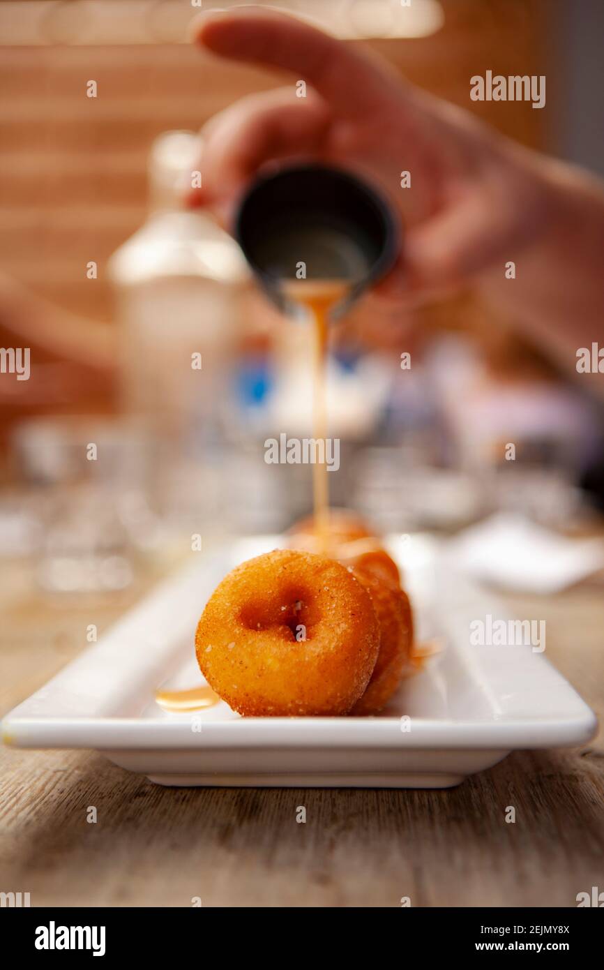 Sweet mini donuts on a white tray with maple syrup and loads of sugar ...