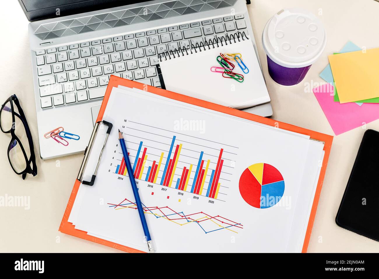 Laptop with financial data charts, glasses, paper clips, and a notebook ...