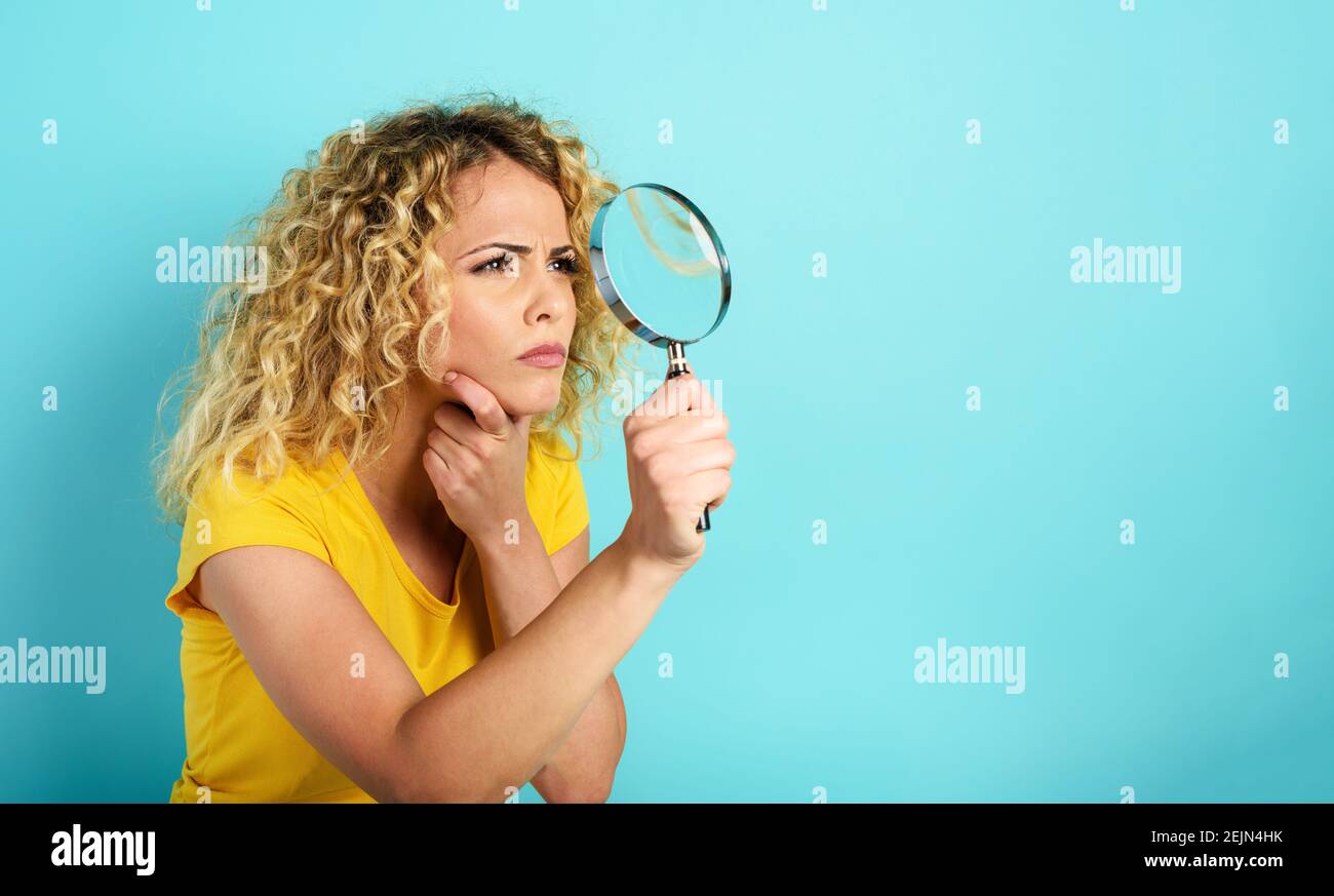 Girl with magnifier lens is distrustful about something. Cyan ...