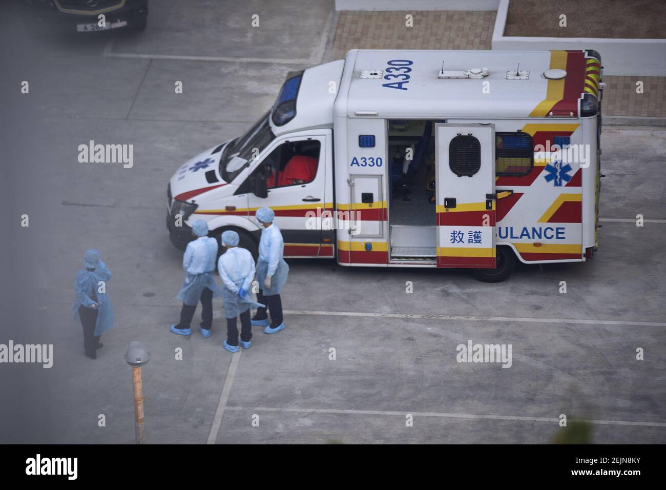 Medical professionals wearing protective gear stand next to an ...