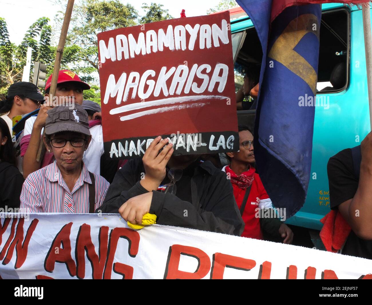 An activist holding a placard saying, Filipino people must unite ...
