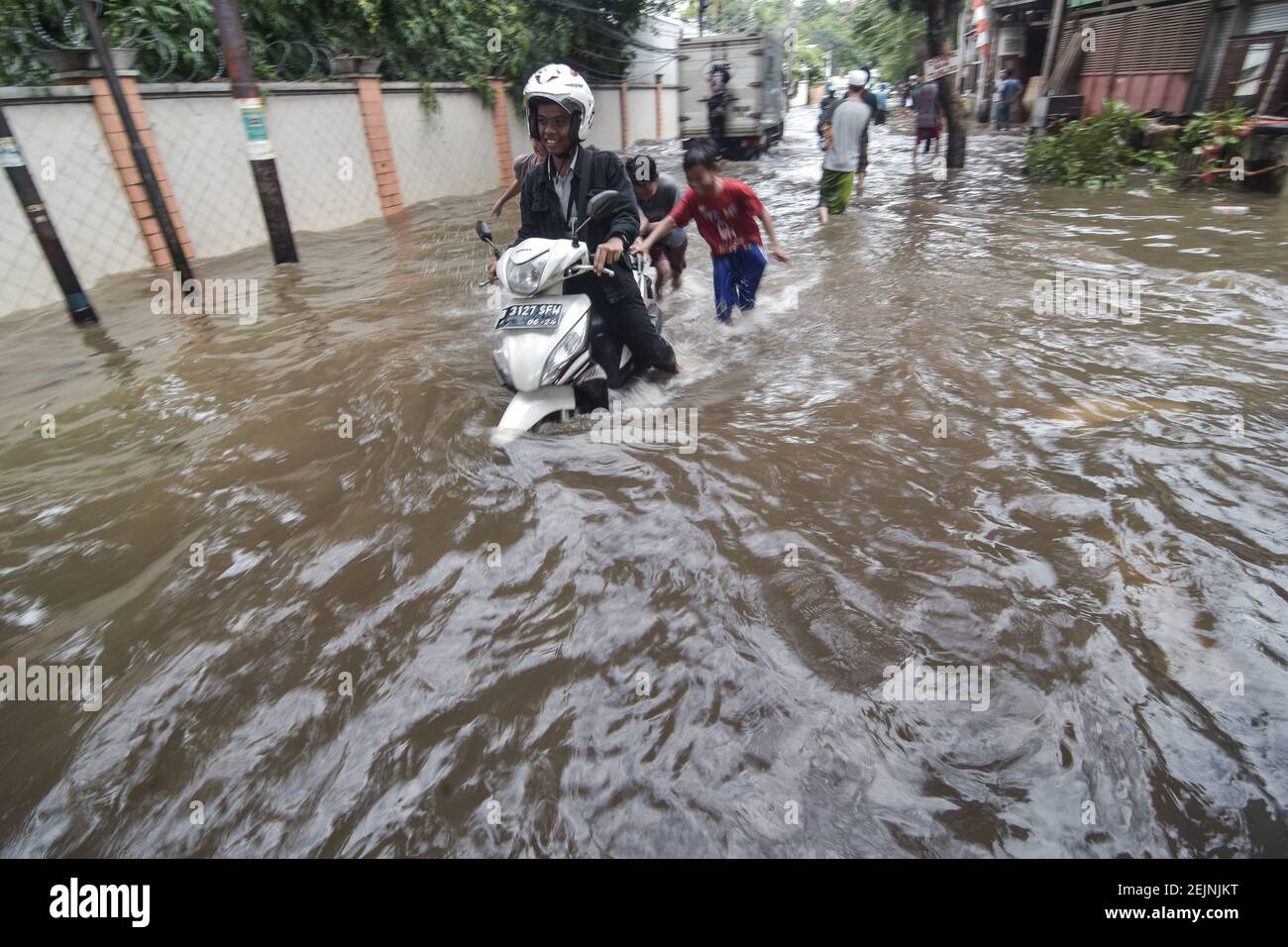 Motorcyclists wade through a waterlogged area in Kemang. Dozens of ...
