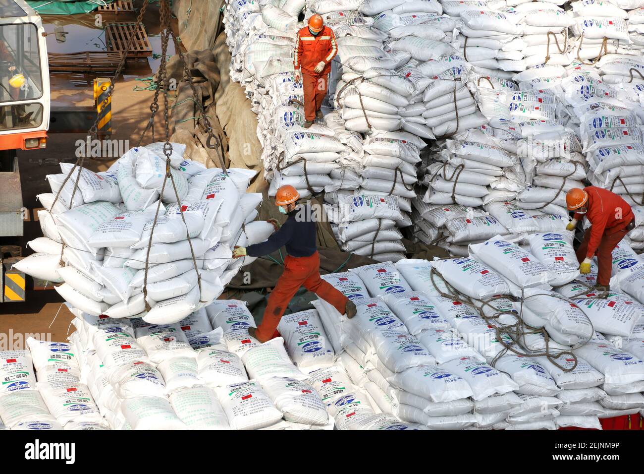 Chinese workers load a truck with sacks of imported fertilizer on the ...