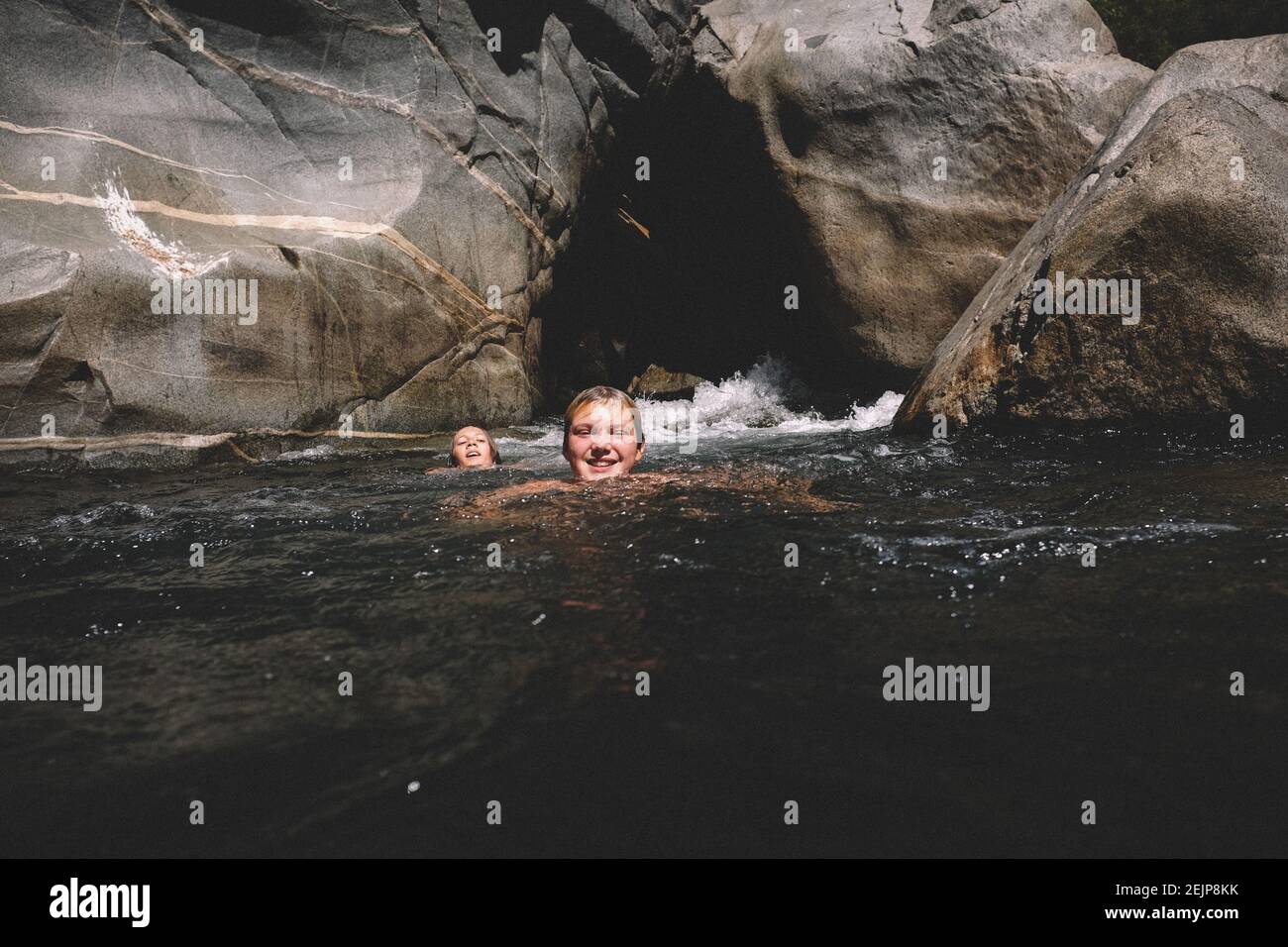 Friends Swimming Together with Boulders and Swirling Water around them ...
