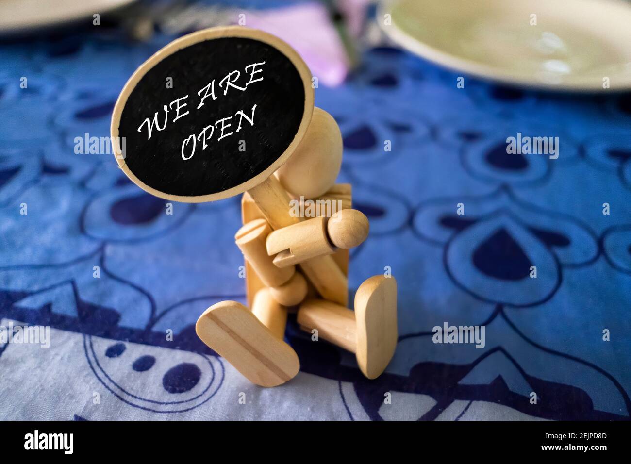 wooden dummy sitting on a restaurant table holding a sign with the ...