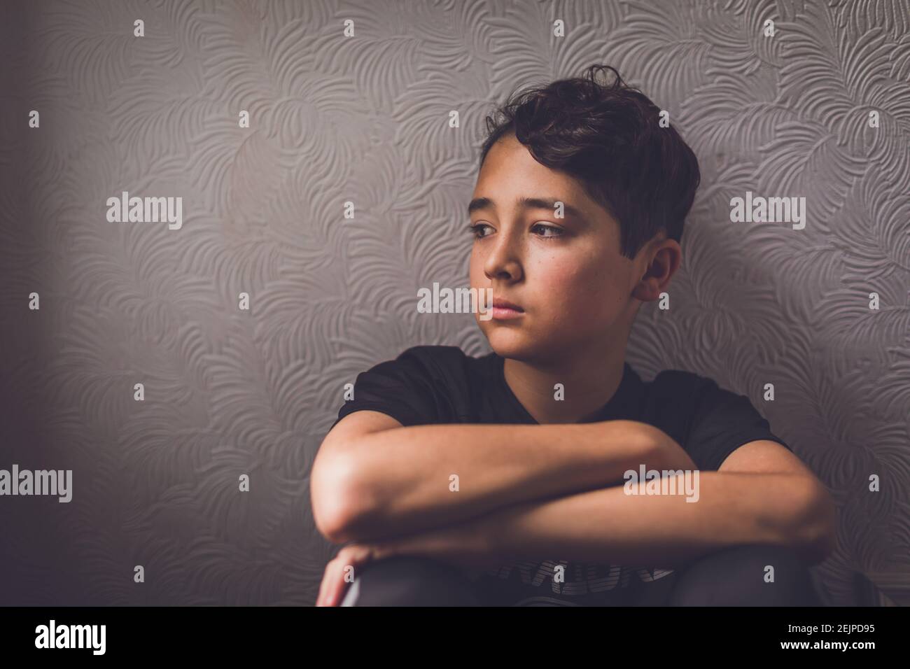 Boy leaning against the wall looking a window Stock Photo - Alamy
