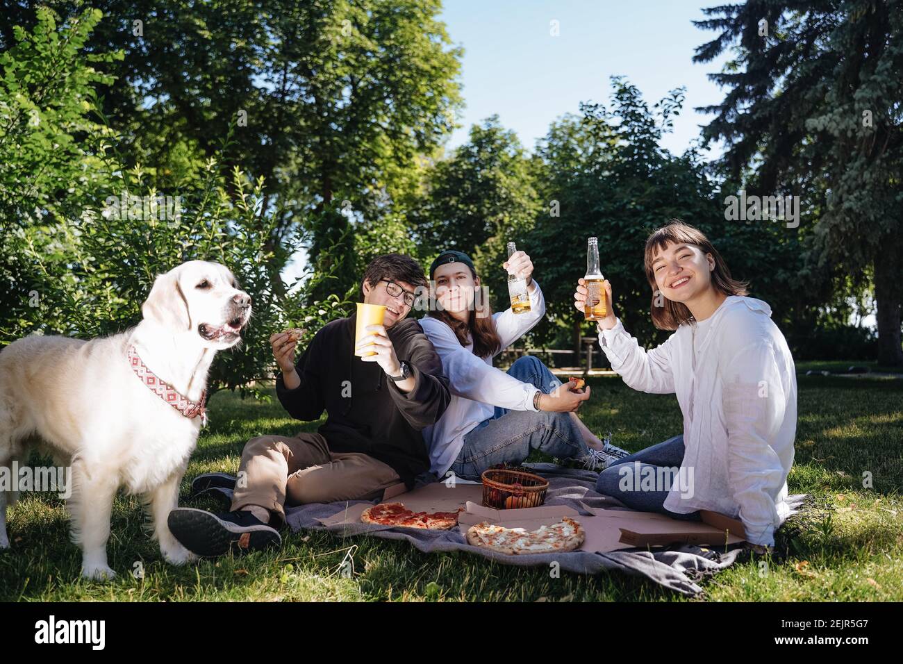 Company of beautiful young people and dog having an outdoor lunch Stock ...