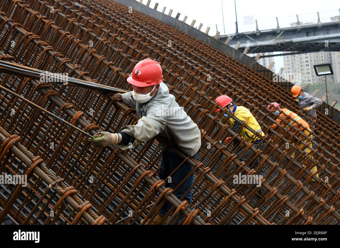 Laborers work to construct a bridge, to ensure the work will be done in ...