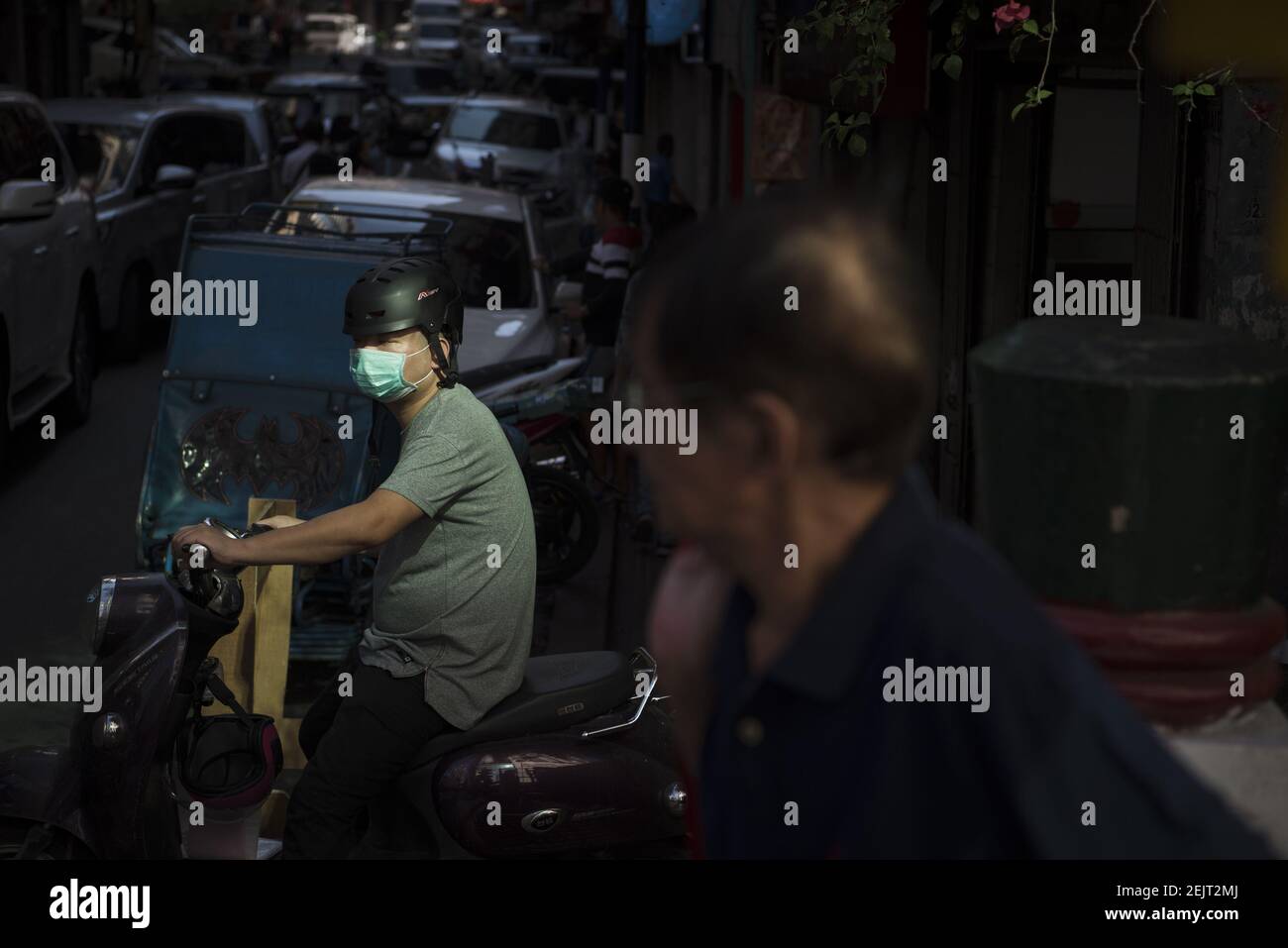 A man riding a motorcycle wears a face mask as a precaution against the ...