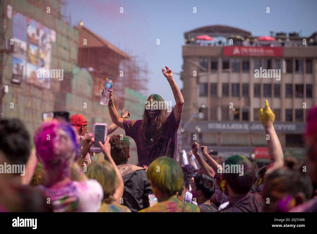 People covered with Vermilion powder celebrate during the festival ...