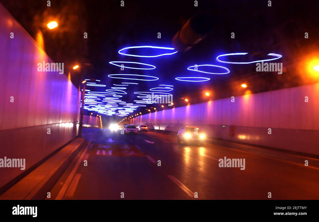 Vehicles move slowly in a 3000-meter-long tunnel, where blue LED light ...