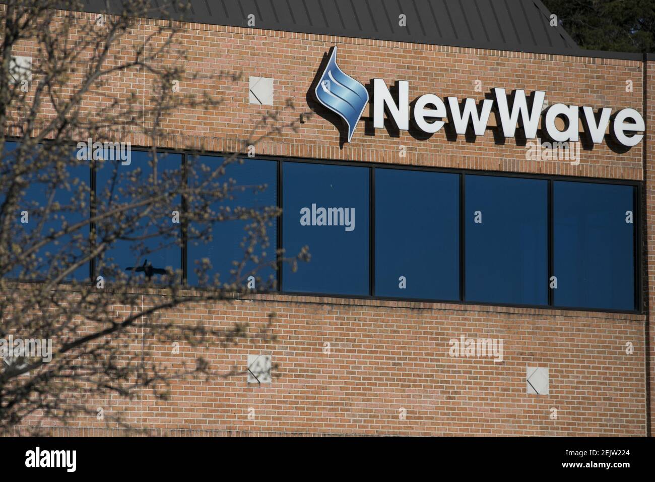 A logo sign outside of a facility occupied by NewWave Telecom ...